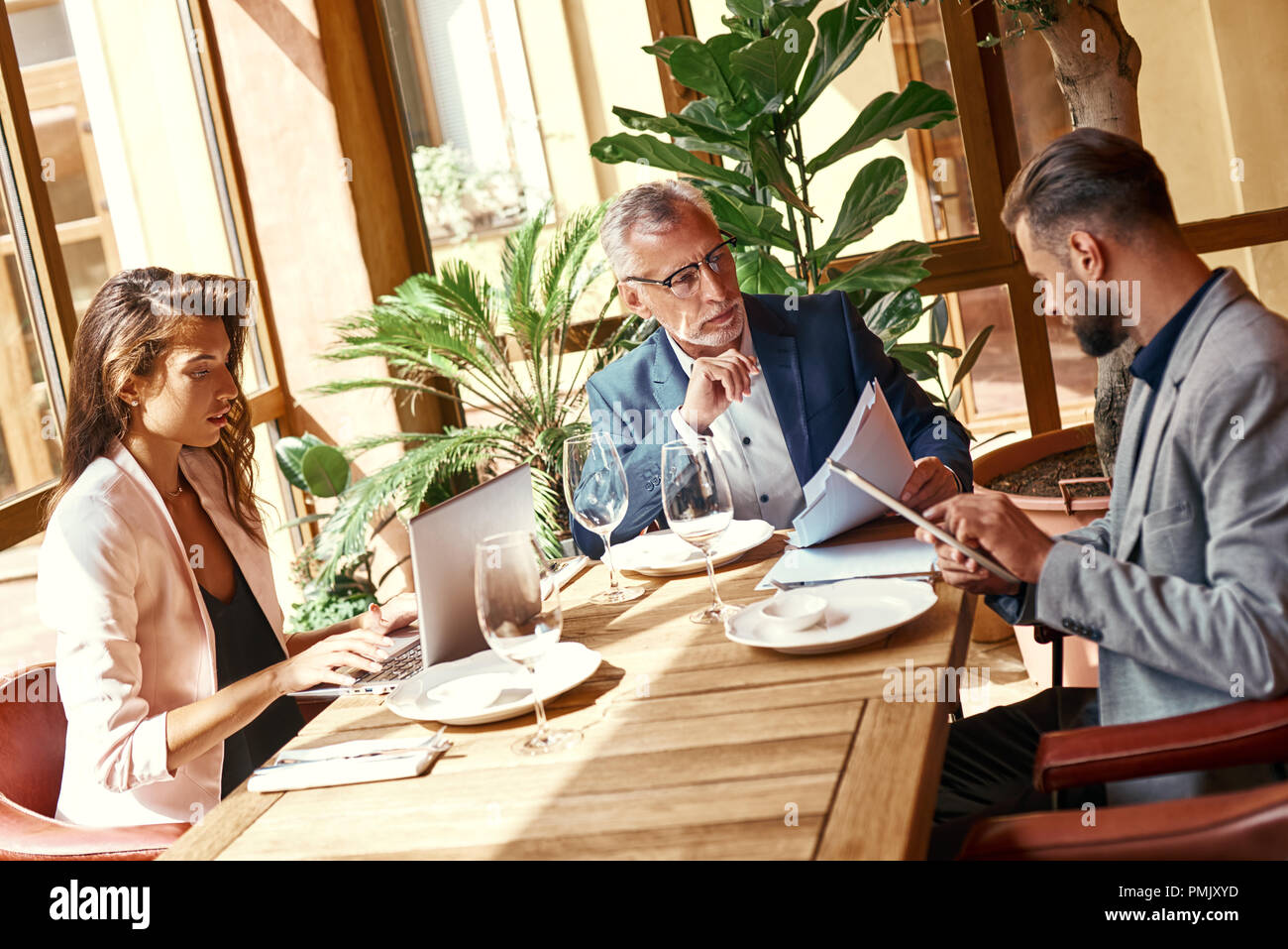 Business lunch. Three people in the restaurant sitting at table ...
