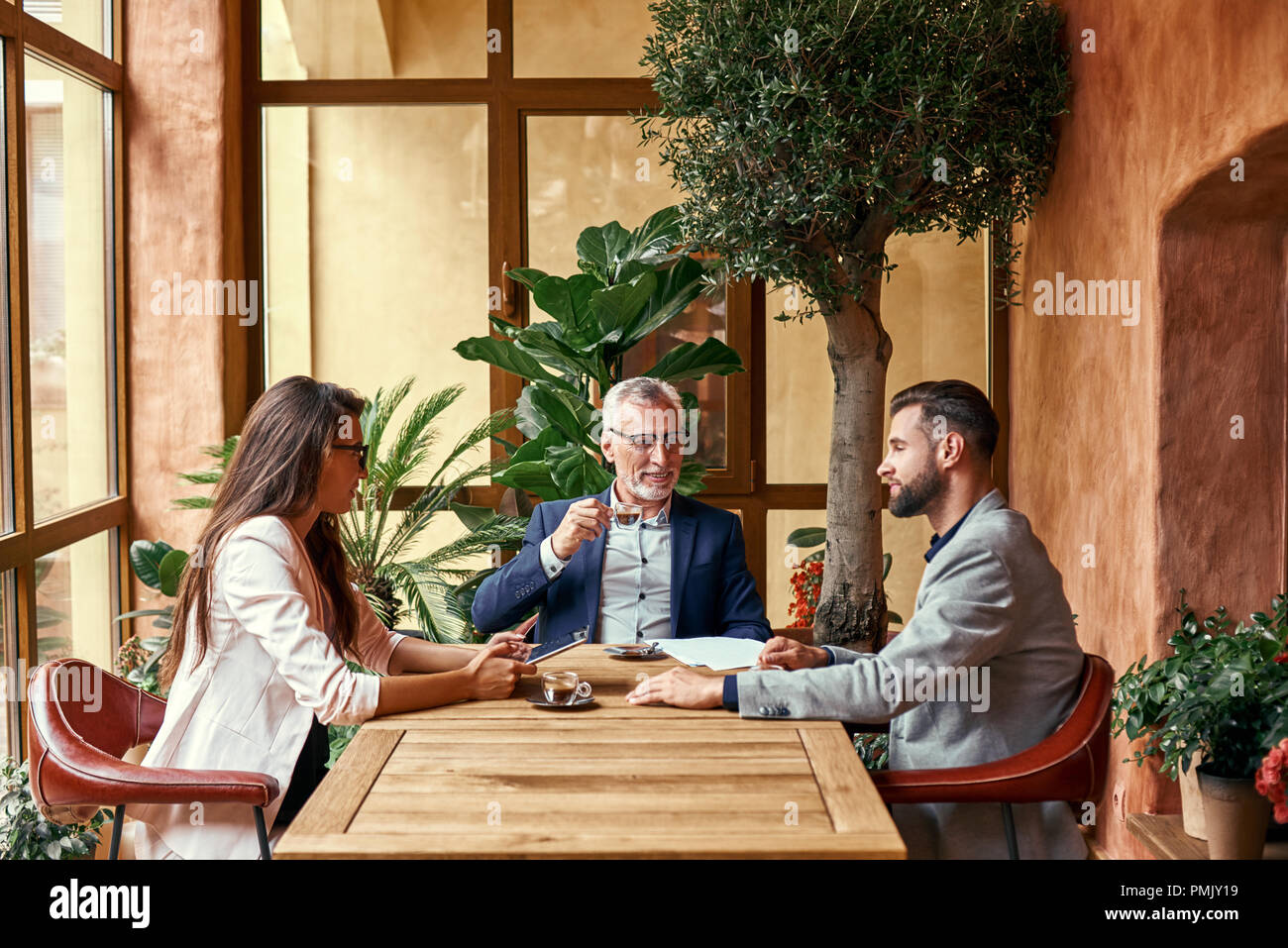 Business lunch. Three people in the restaurant sitting at table ...