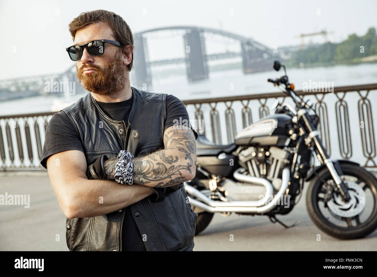 Redhead biker with beard in leather jacket standing with crossed arms ...