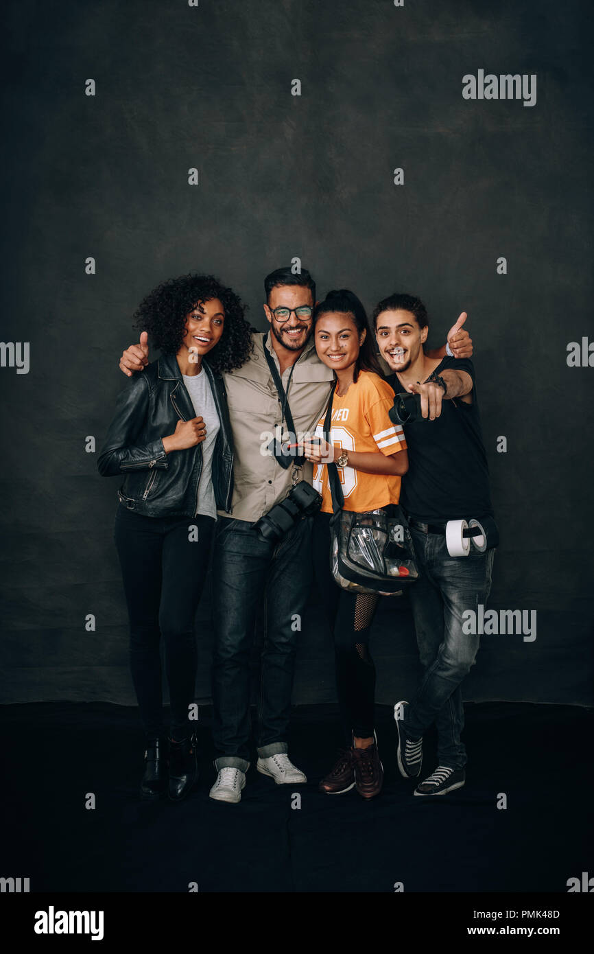 Studio shot of photographer standing with his arms around his crew ...