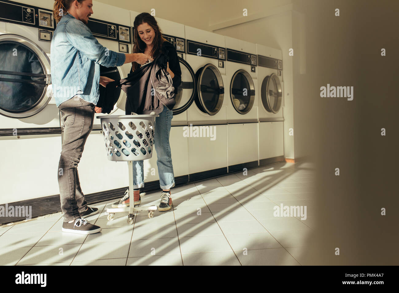 Cheerful couple doing laundry together in a laundry room. Smiling ...