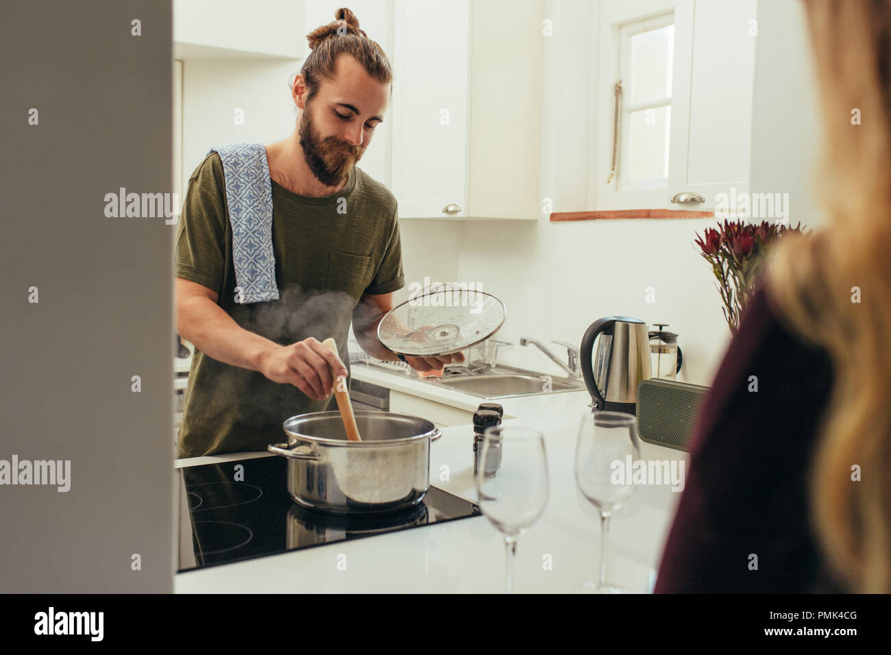 Man preparing dinner standing in kitchen. Couple in kitchen making food ...