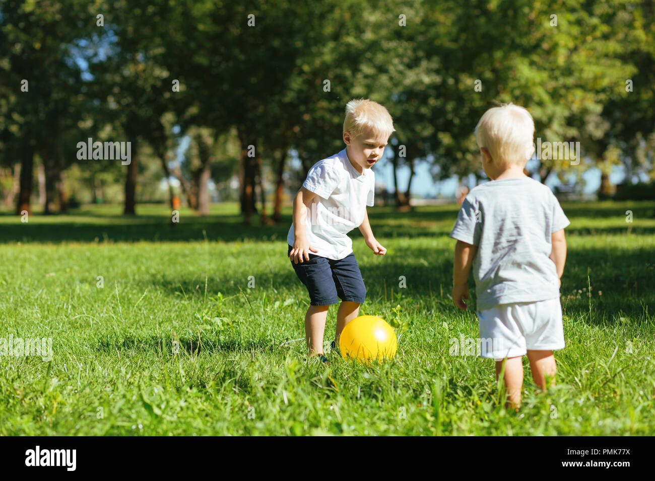 Cute brothers playing with a ball together in the garden Stock Photo ...