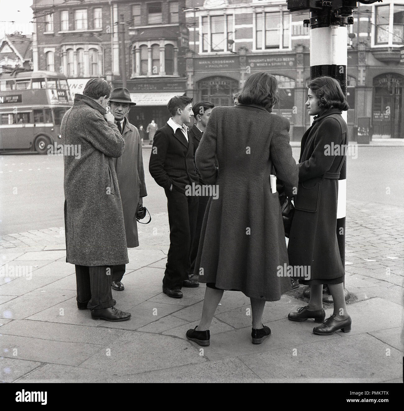 1950s, London, England, group of people, some wearing coats, gather ...