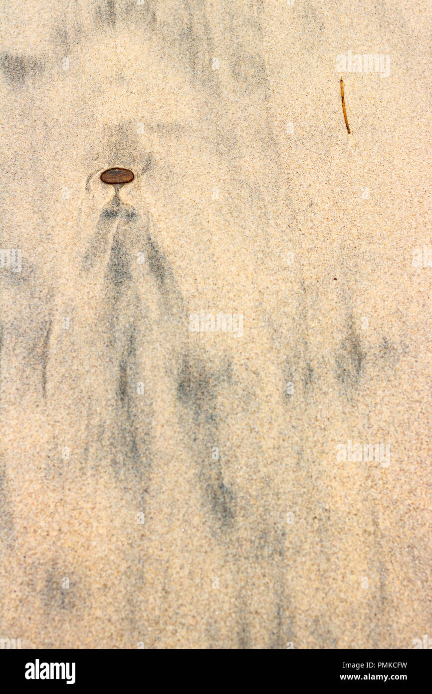 Black silt patterns in beach sand looking like alien, angel person ...