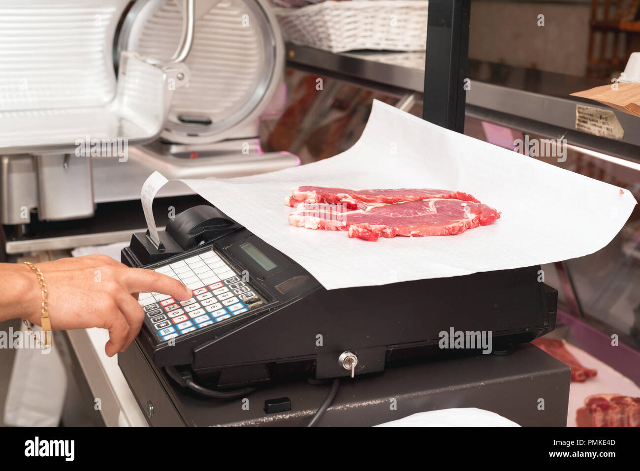 Butcher weighing meat at display cabinet in the butchery Stock Photo ...