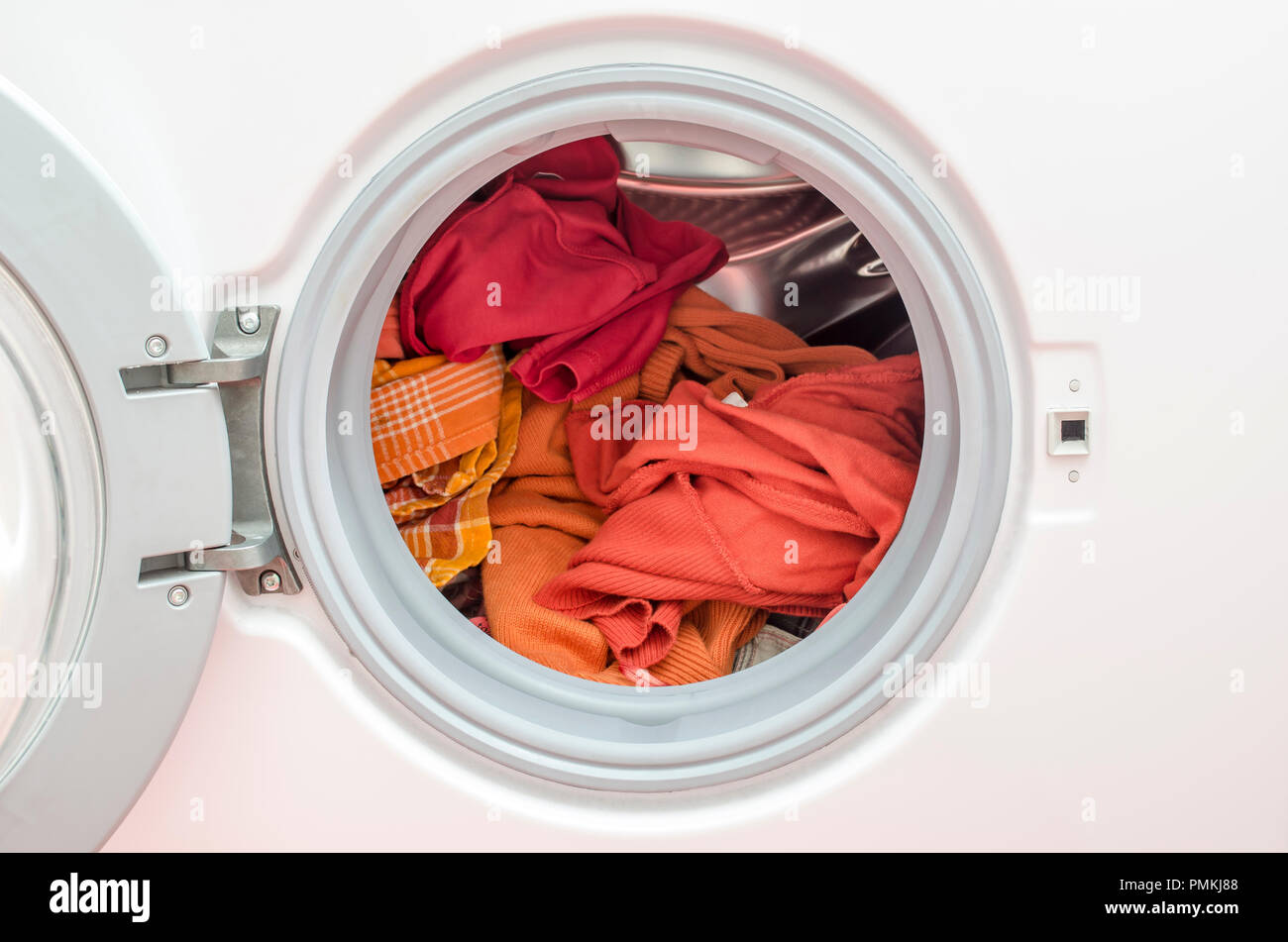 Close up of a washing machine loaded with red clothes Stock Photo - Alamy