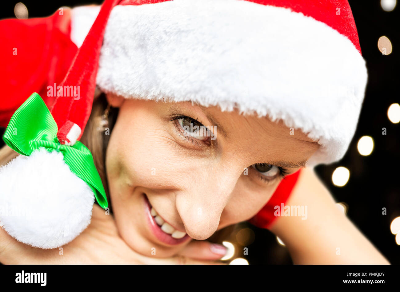 Portrait of cheerful miss Santa with blurred christmas lights in ...