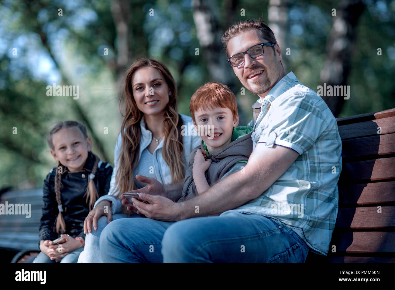 happy family sitting on bench in summer Park Stock Photo - Alamy