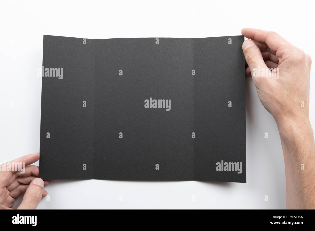 Mens hands holding empty black booklet on white background. View from ...