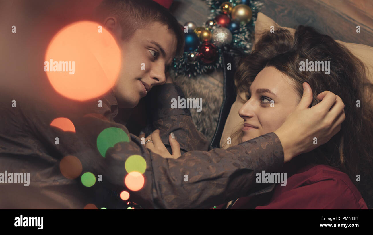 Loving couple celebrating Christmas. They are lying on couch. Guy ...