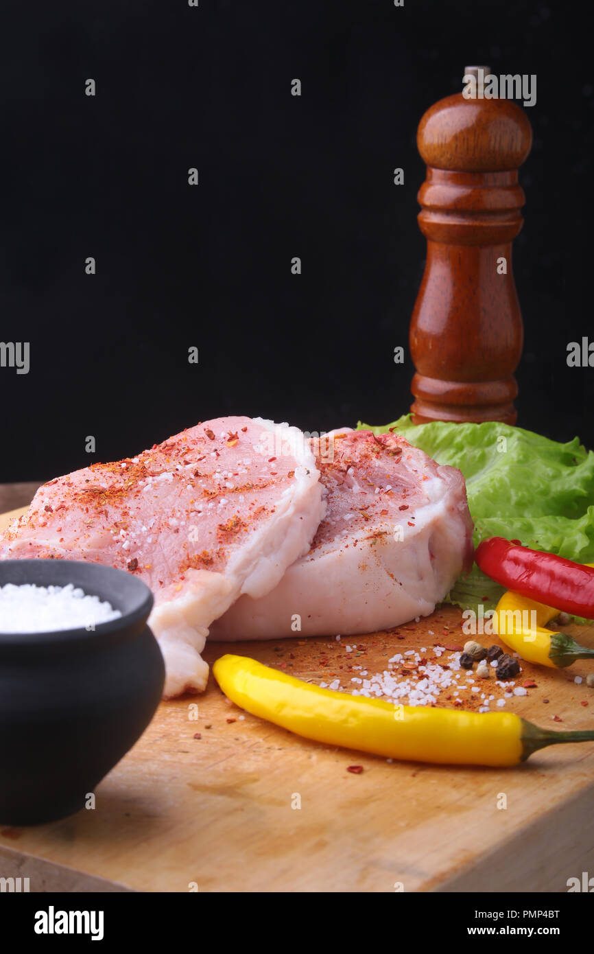 Raw steak, chop on a rustic cutting board with salt, pepper and grinder ...
