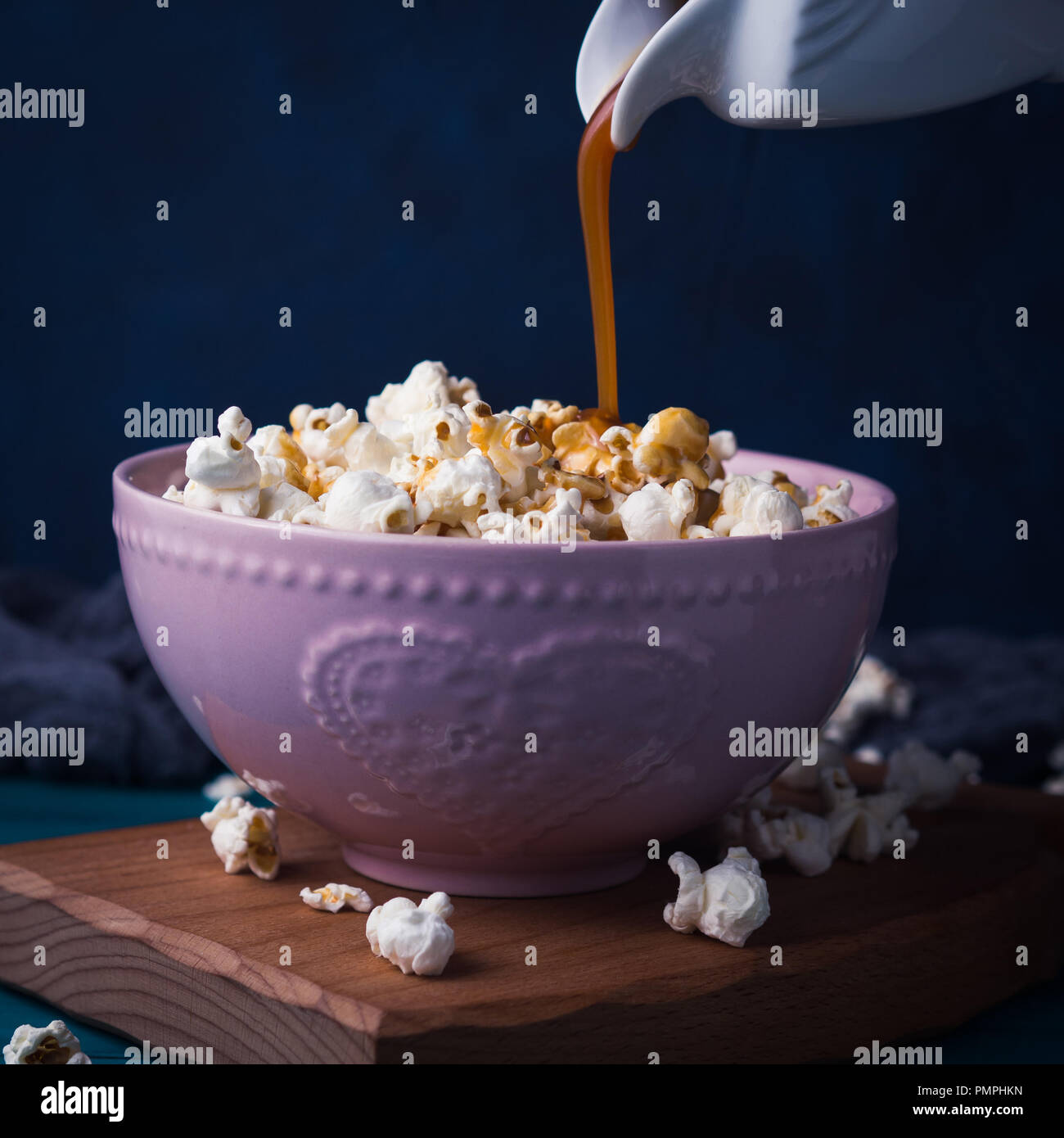 Pouring salted caramel on popcorn in bowl. Dark still life Stock Photo ...