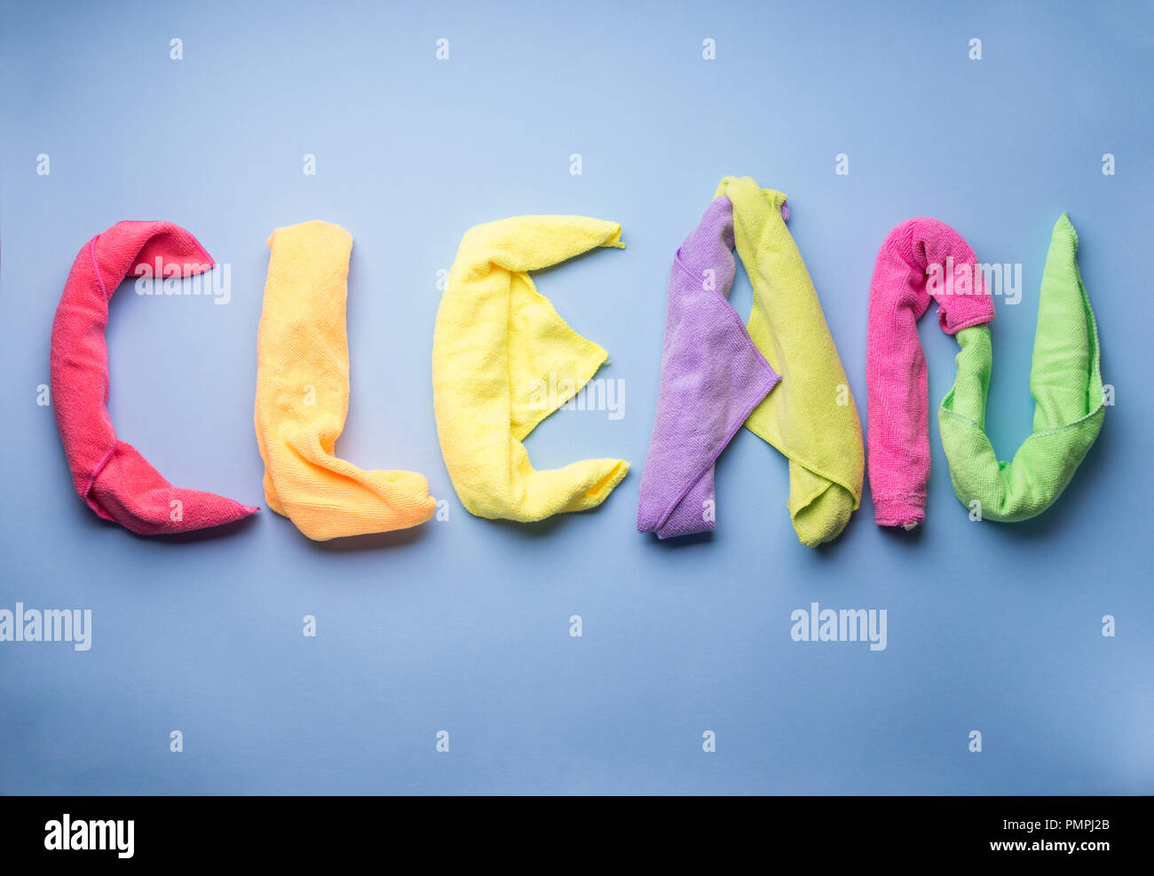 Word Clean written with cleaning cloths as letters on blue pastel ...