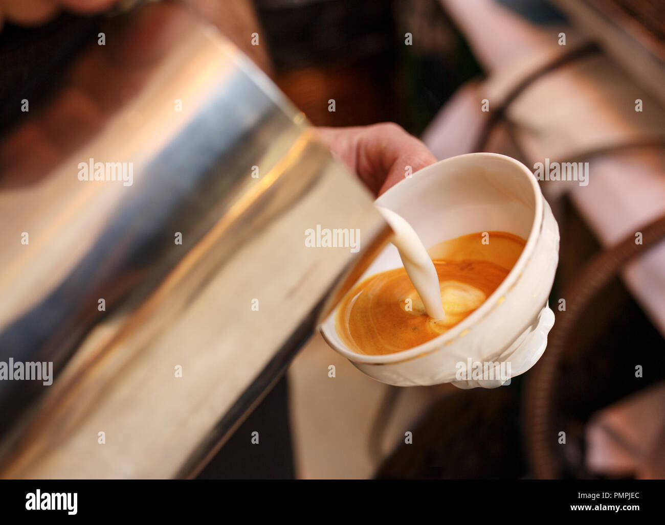 Barista in coffee bar preparing proper cappuccino pouring frothed milk ...