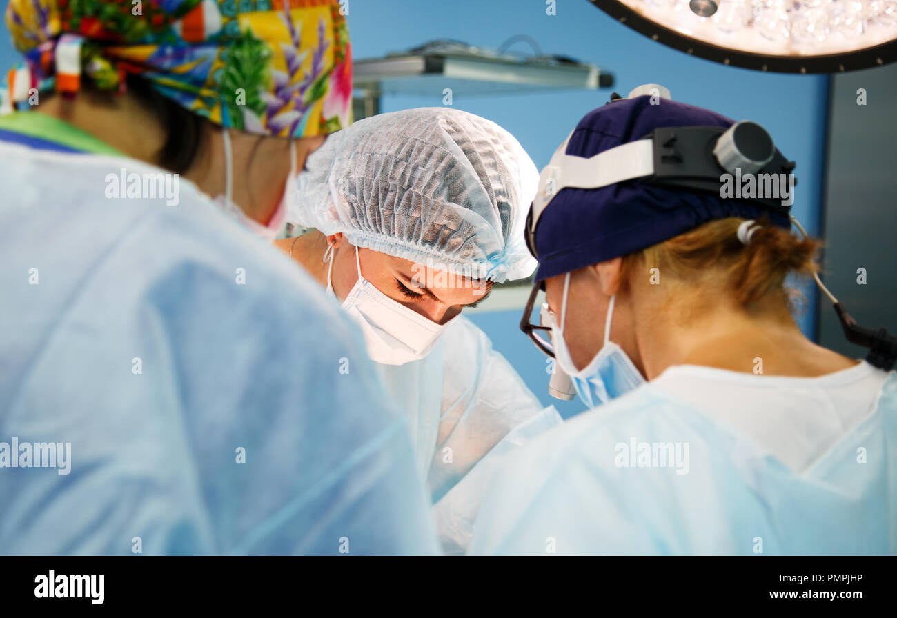 Surgery, medicine and people concept - three surgeons in operating room ...