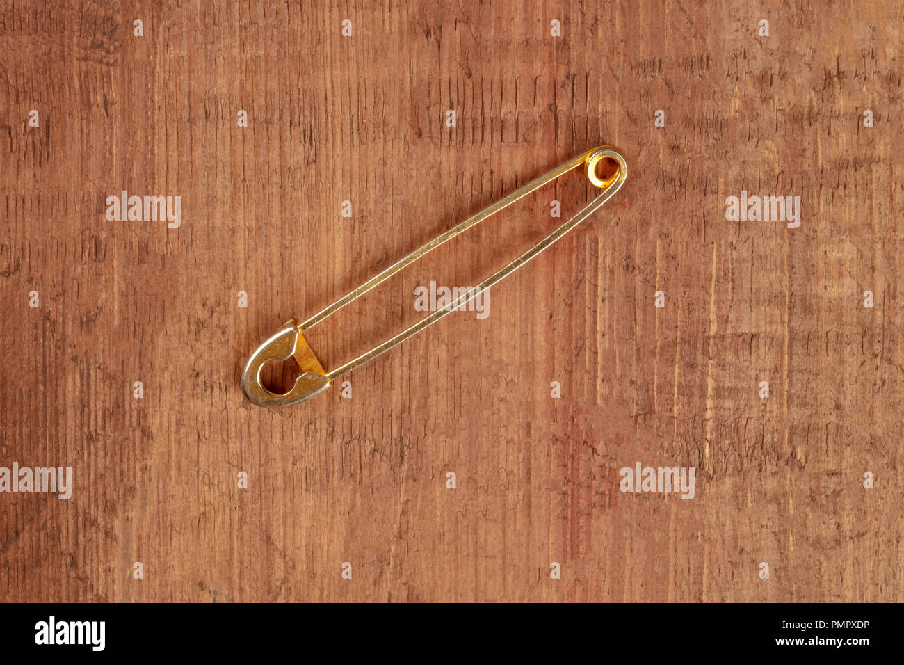 An overhead photo of a vintage safety pin, shot from above on a dark ...
