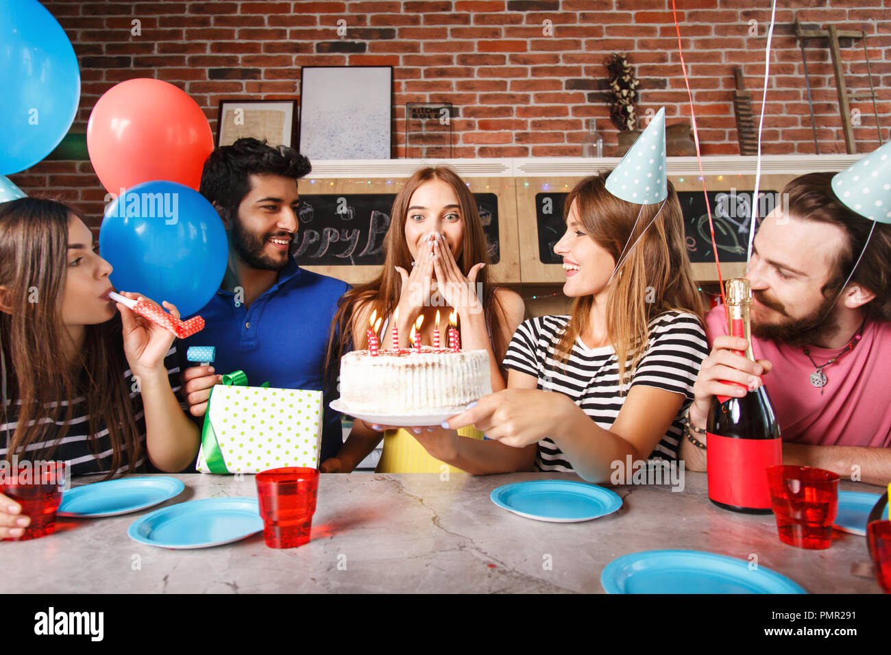 Cute young woman surprised while her friends bring the cake Stock Photo ...