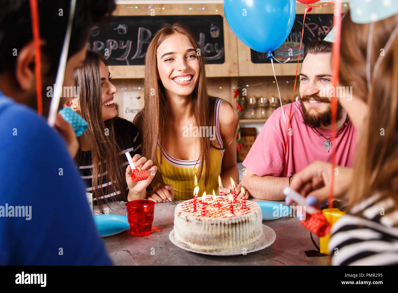 Brunette long hair girl sitting around her friends and smiling a lot on ...