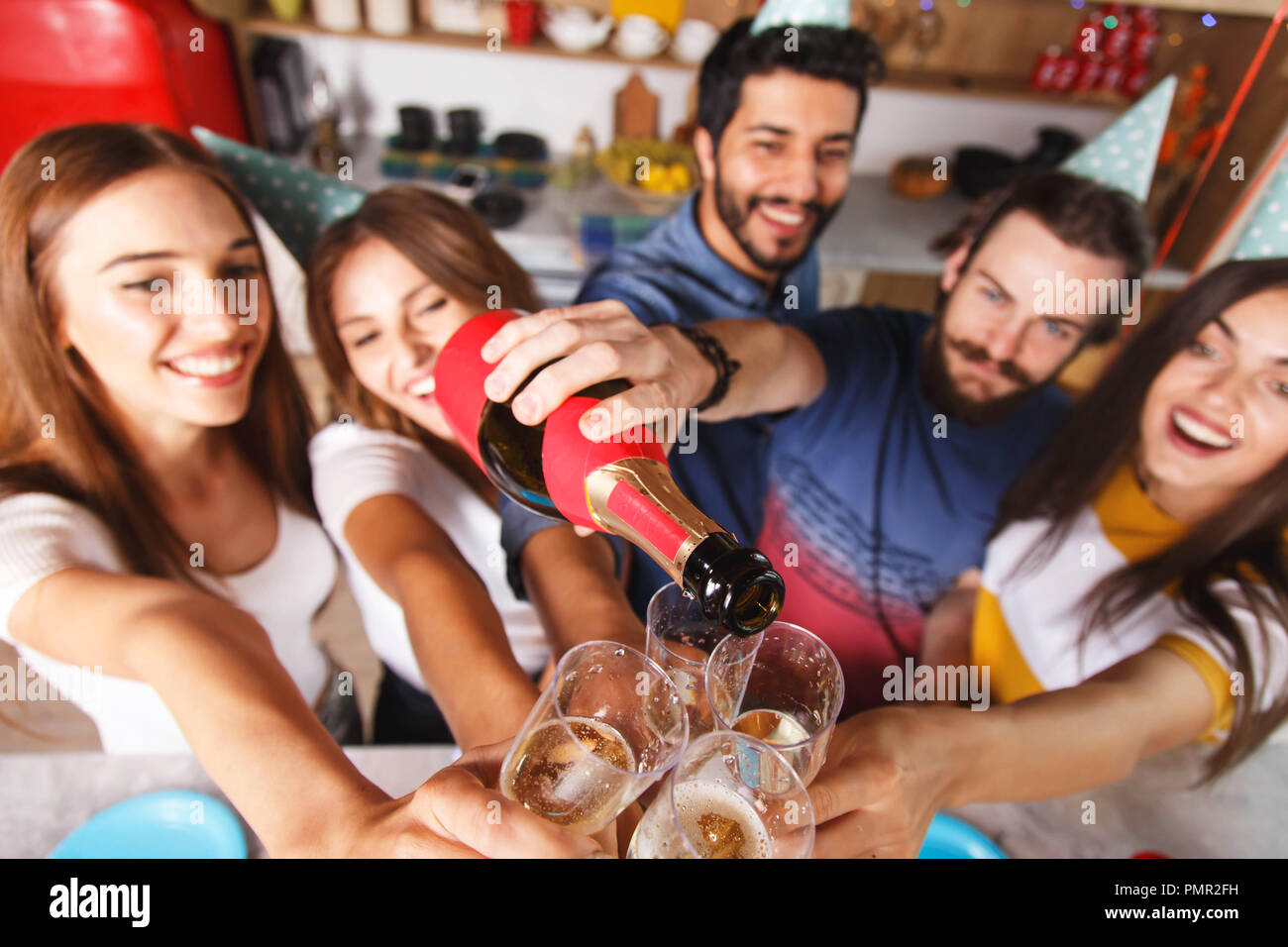 Group of cheerful friends having a party at the kitchen and drinking ...