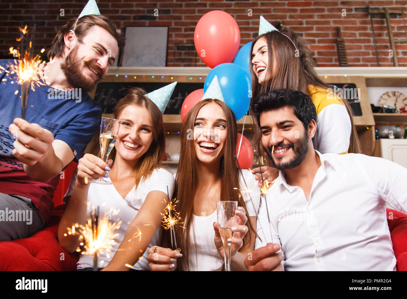 Best friends in the party hats drinking champagne, holding sparklers ...