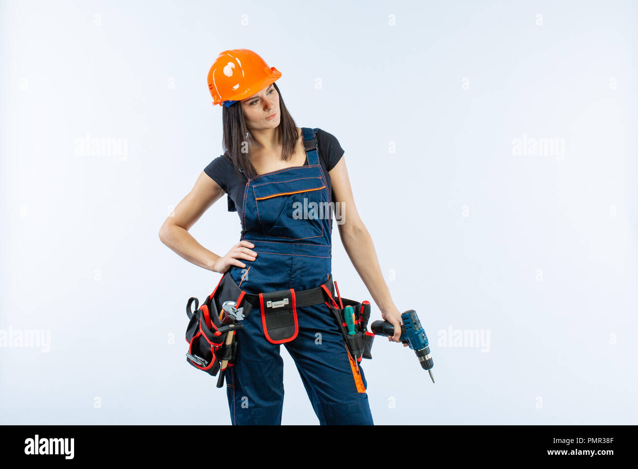 Young woman with toolbelt using driil and some power tools for her work ...