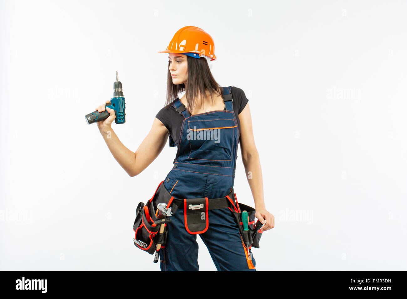 Young woman with toolbelt using driil and some power tools for her work ...