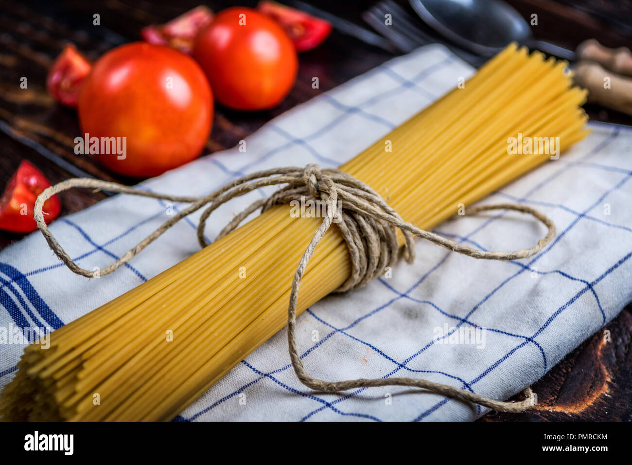 Raw Italian pasta spaghetti and tomatoes on dark wood table Stock Photo ...