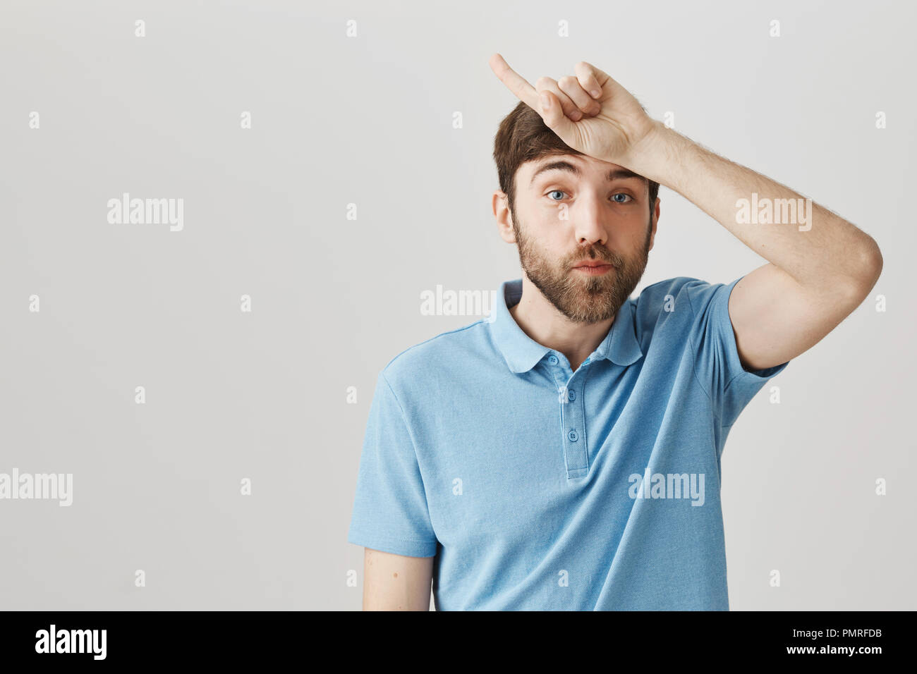 Bored young adult with beard and moustache holding hand over forehead ...