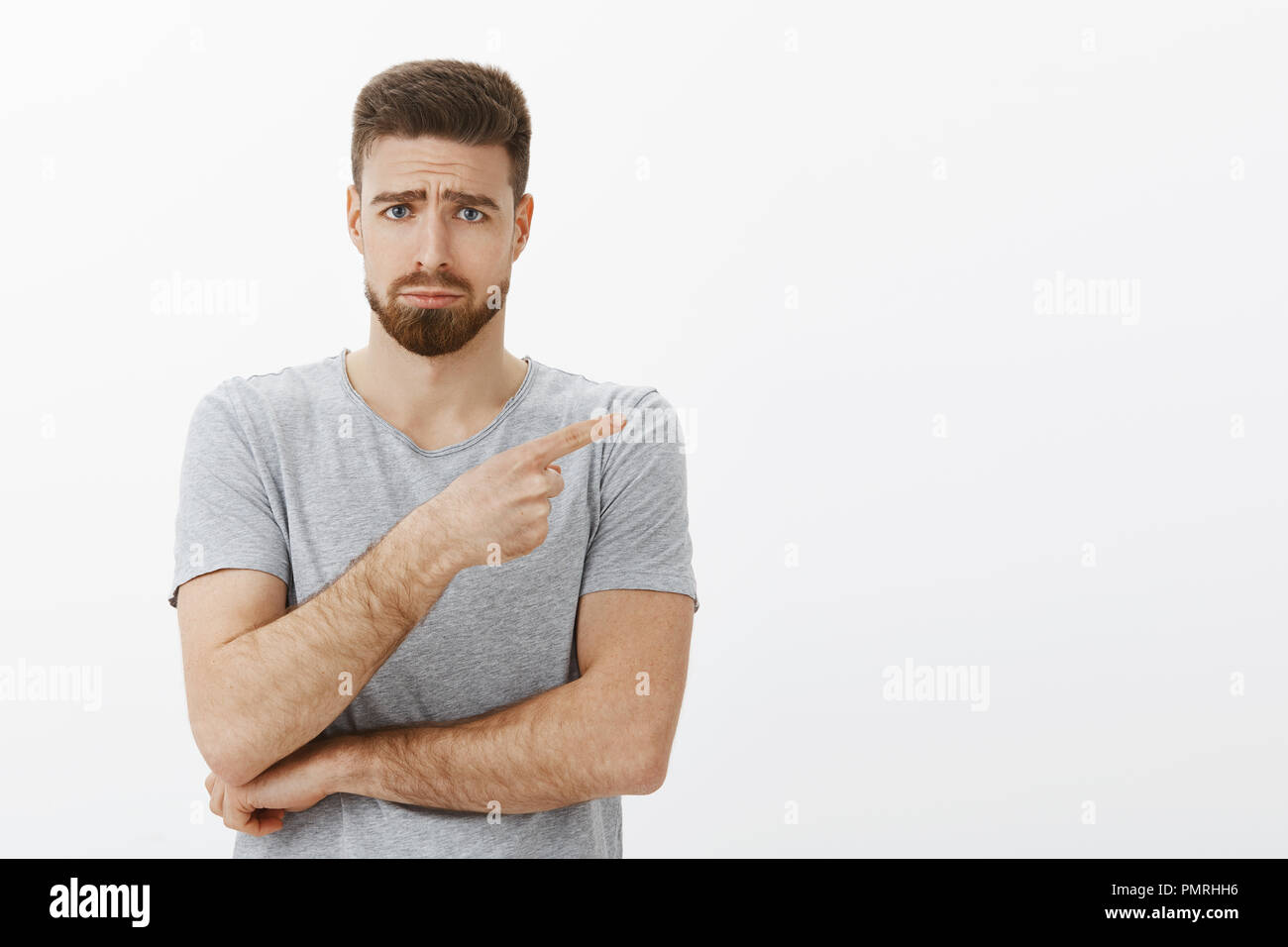 Sad and cute charming bearded male model in grey t-shirt frowning ...