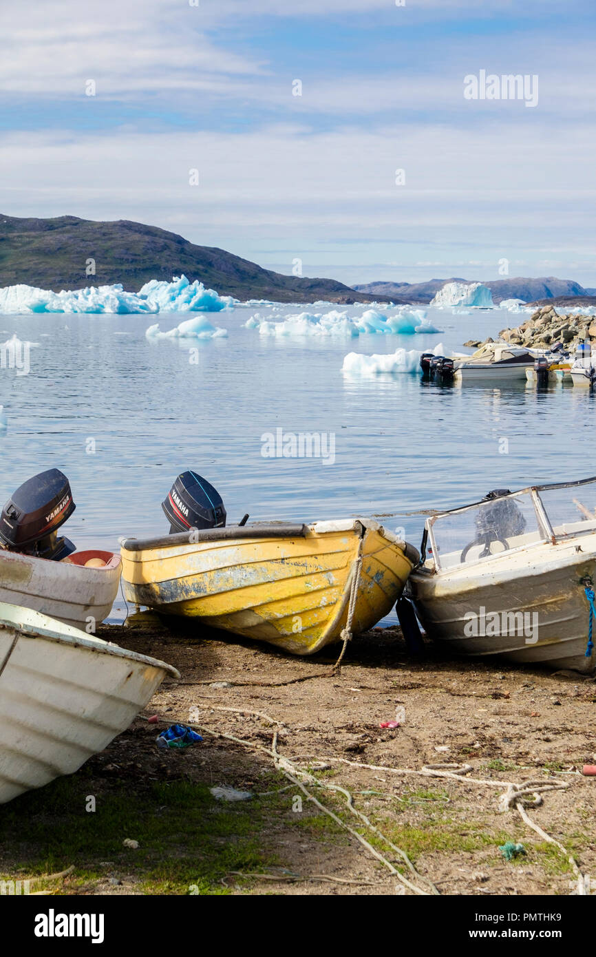 Small Inuit fishing boats in Qajaq Harbour with icebergs offshore in ...