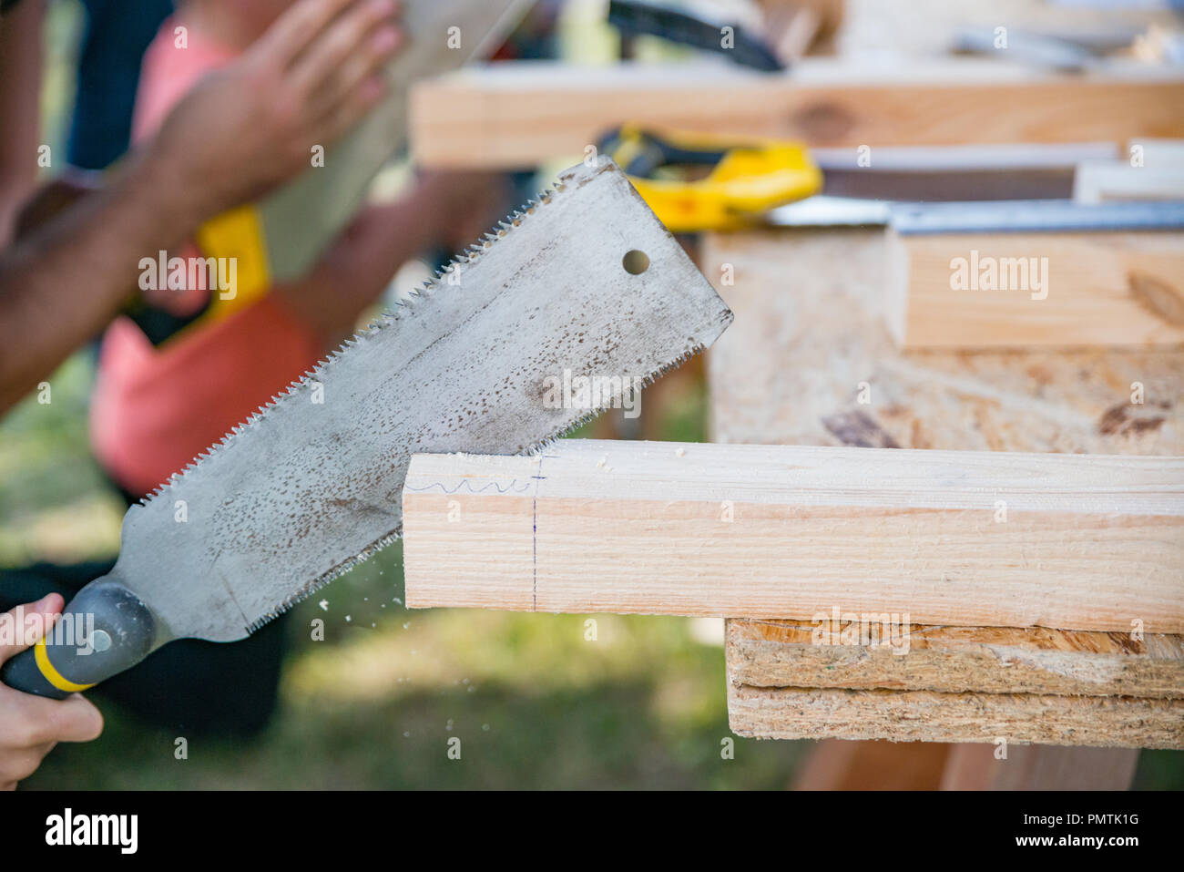 Carpenter cutting wooden plank with manual saw. Wood work Stock Photo ...