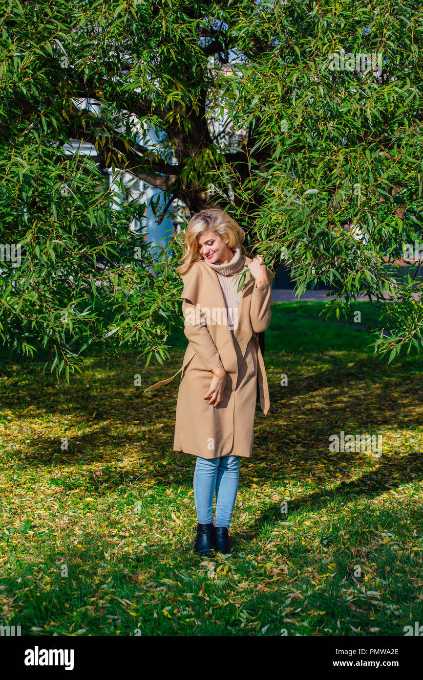 Beautiful elegant blonde woman dressed in a coat standing under the ...