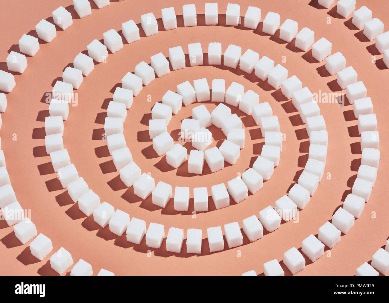 Sugar cubes forming spiral pattern on peach background Stock Photo - Alamy