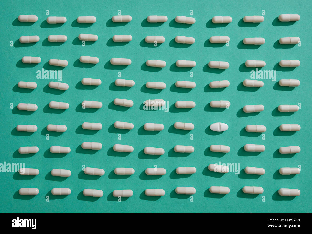 Pill standing out from crowd of capsules on green background Stock ...