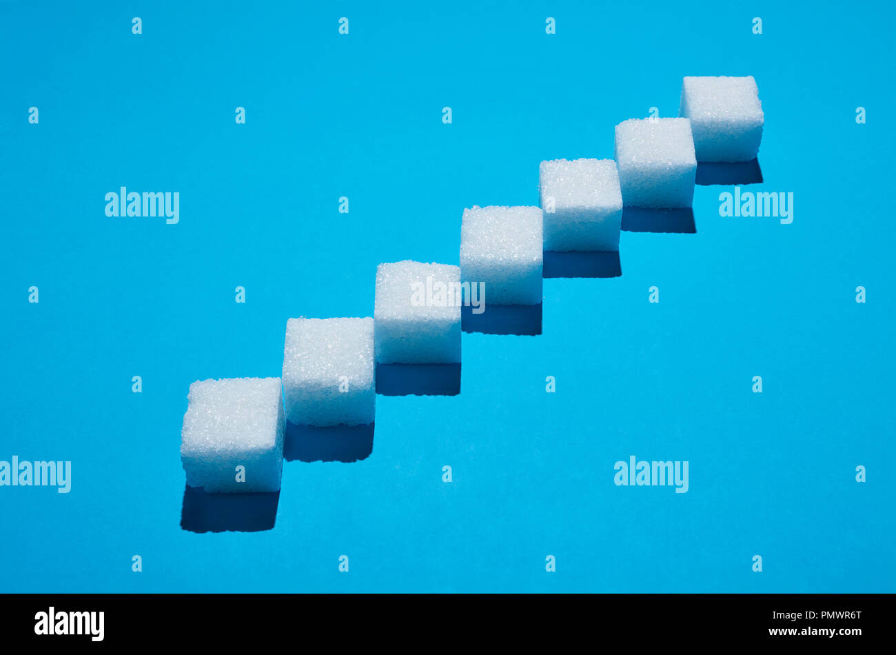 Sugar cubes forming pattern on blue background Stock Photo - Alamy