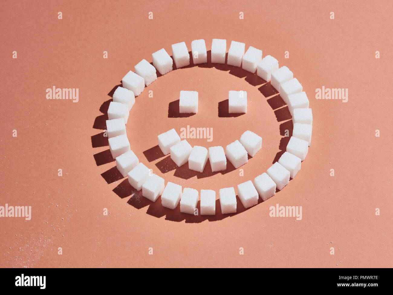 Sugar cubes forming smiley face on peach background Stock Photo - Alamy