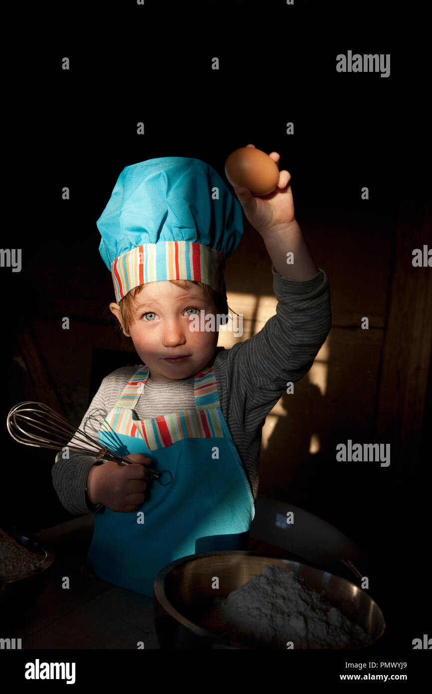 Portrait cute girl in chefs hat baking, holding egg Stock Photo - Alamy