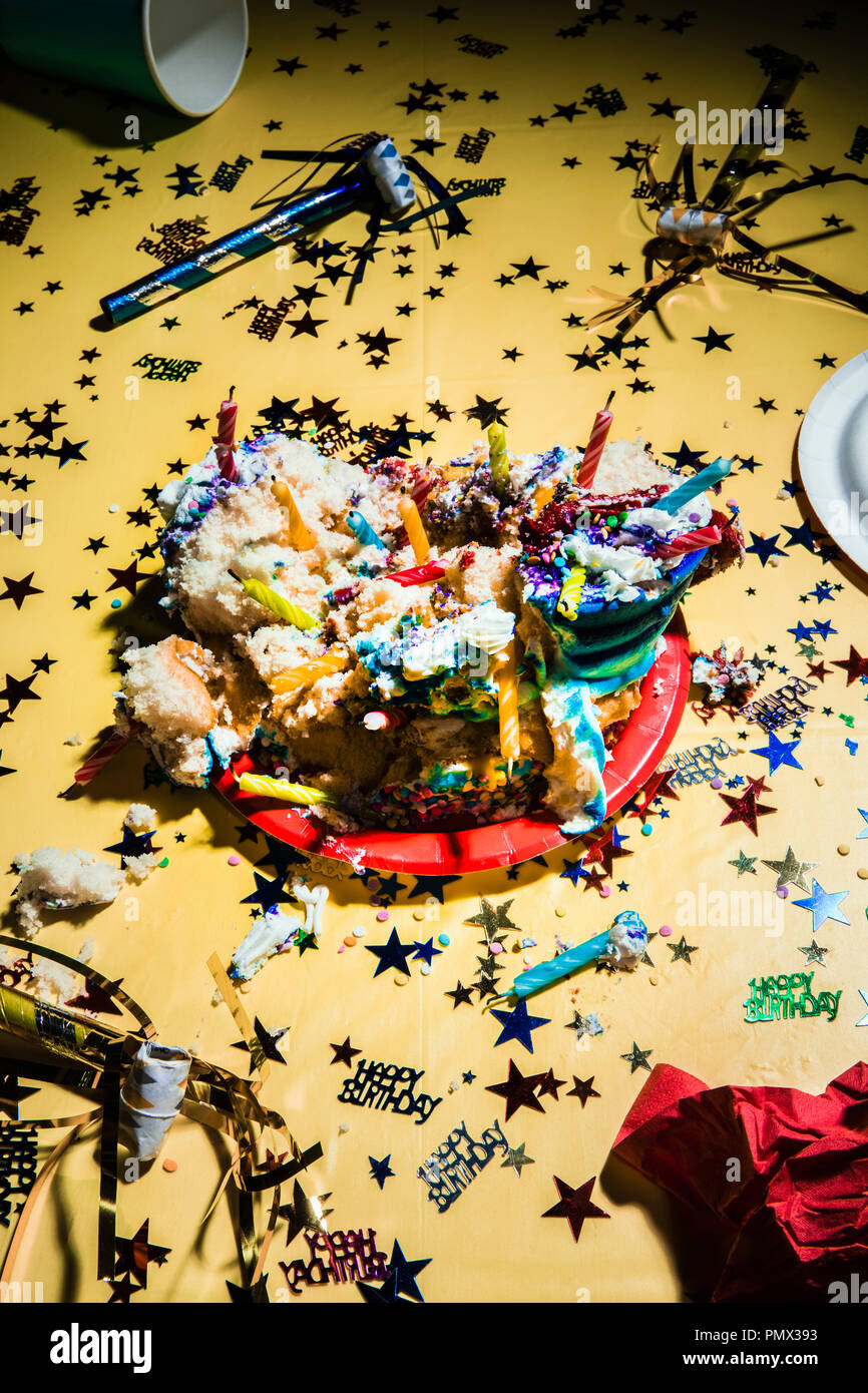 Messy birthday cake and confetti on yellow background Stock Photo - Alamy