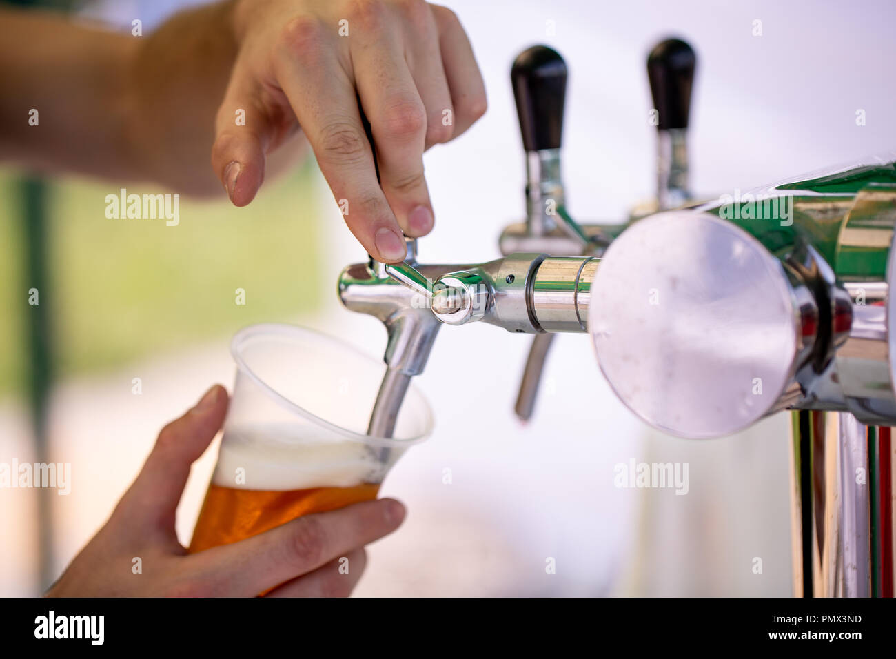 close-up of barman hand at beer tap pouring a draught lager beer in a ...