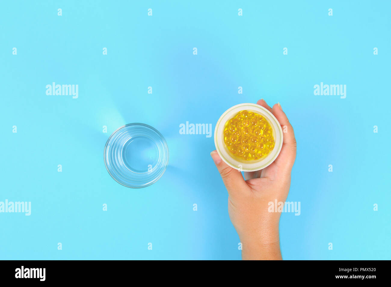 Swallowing tablets. Pills and a glass of water against a blue table ...