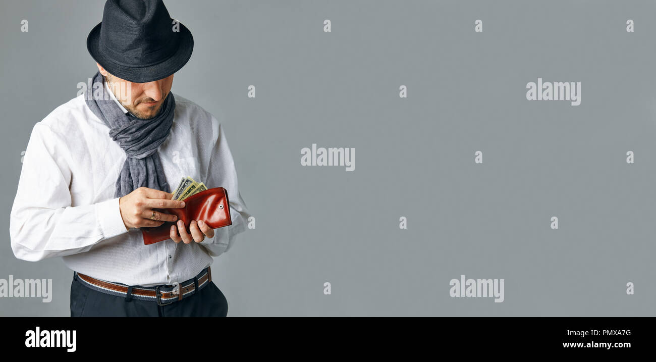 studio portrait of a man who looks how much money he has in his wallet ...