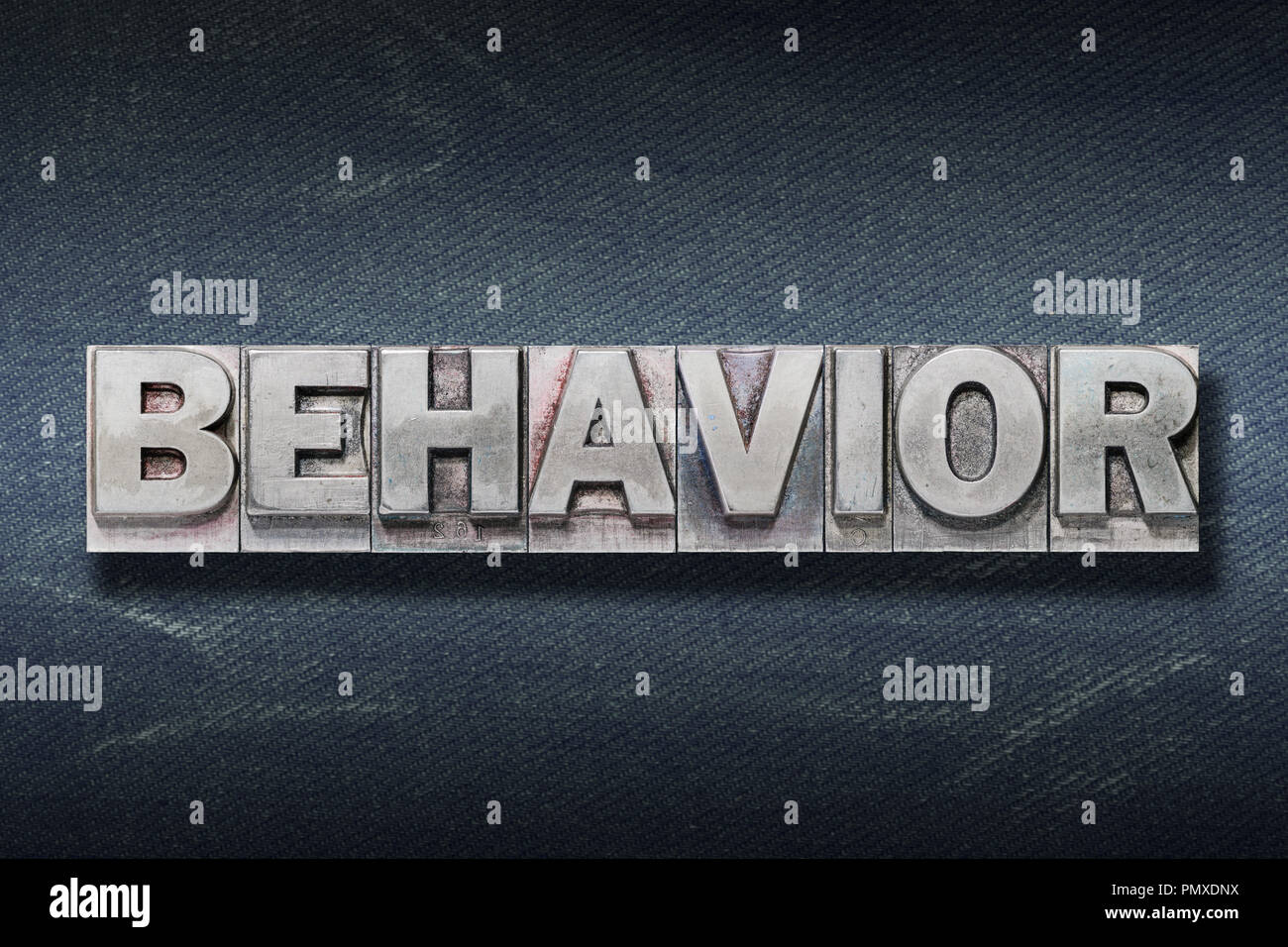 behavior word made from metallic letterpress on dark jeans background ...