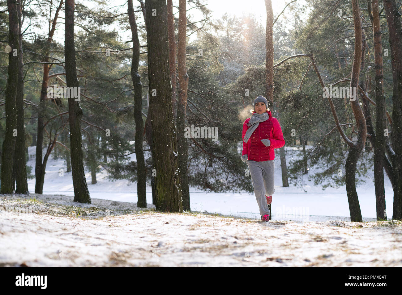Female runner jogging in cold winter forest wearing warm sporty running ...