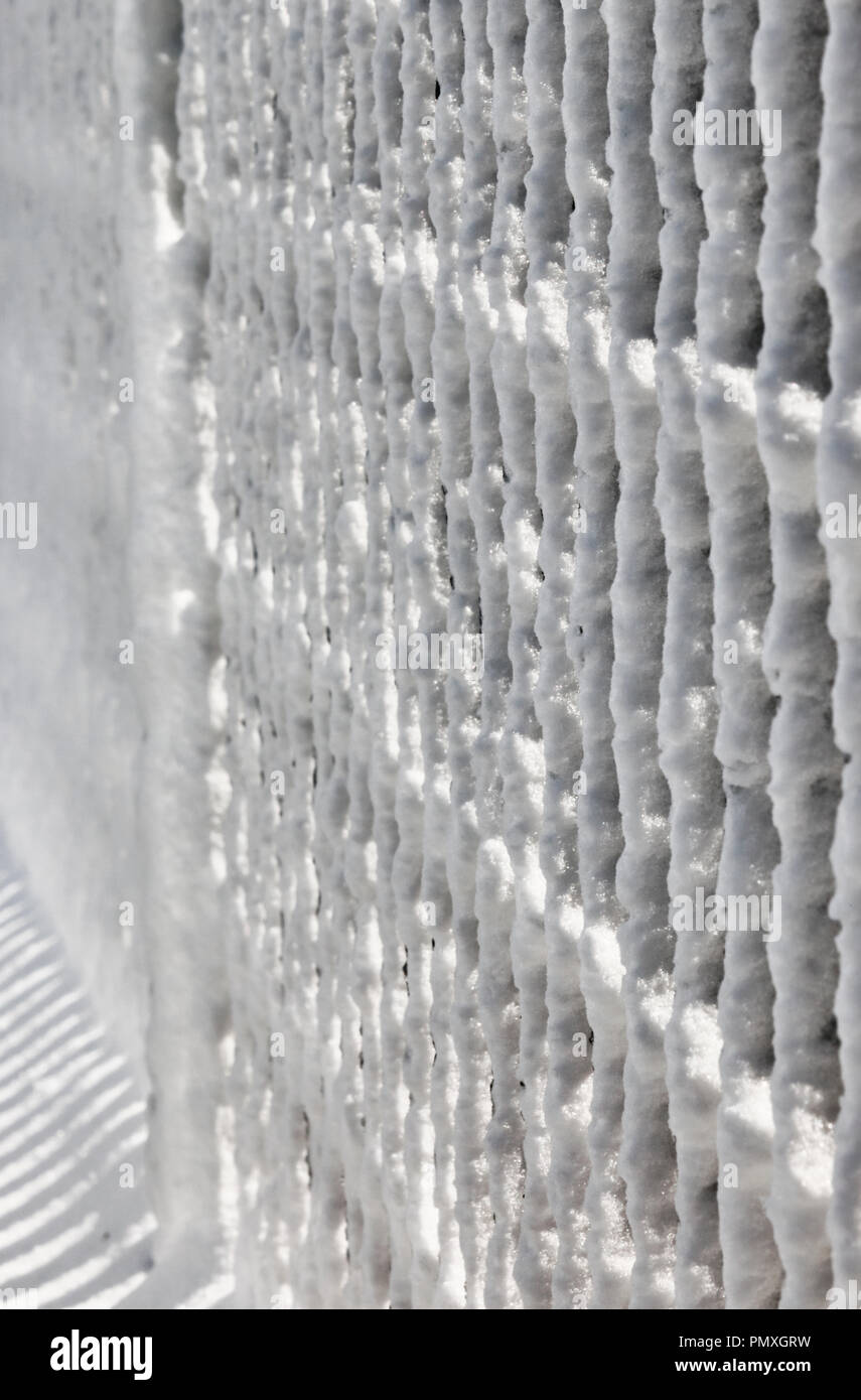 The sun comes through the iron gate covered with snow , in the picture ...