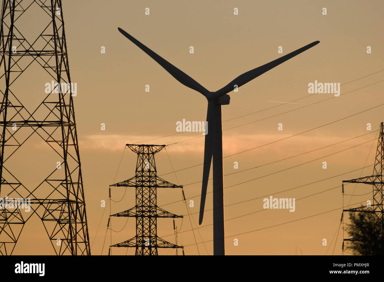 Wind turbine and pylons at sunset Stock Photo - Alamy