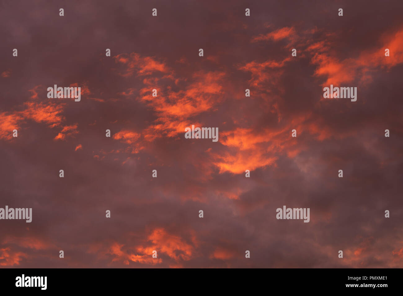 Dramatic blood red crimson sunset reflected off base of clouds against ...