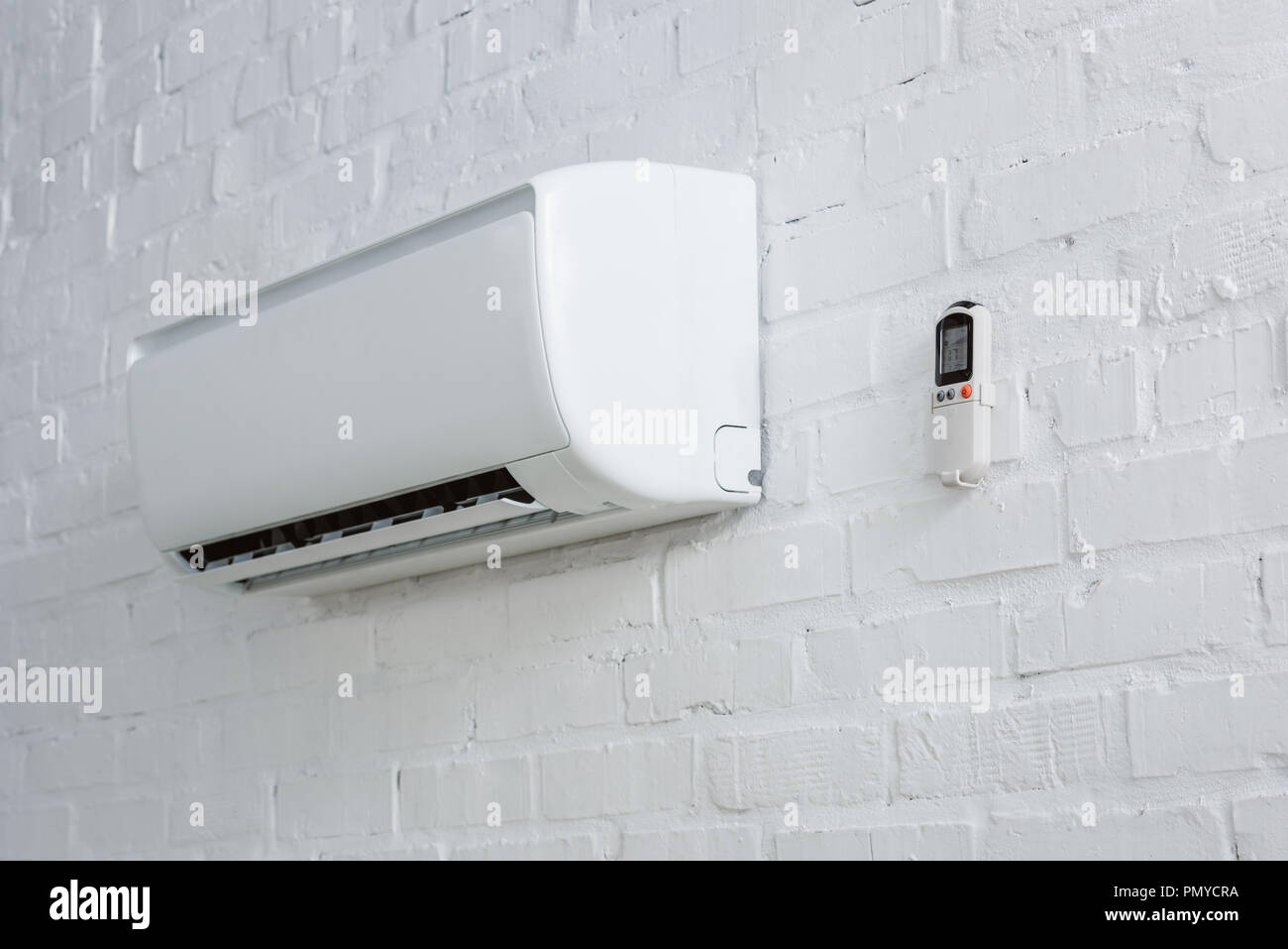 air conditioner hanging on white brick wall with remote control Stock ...
