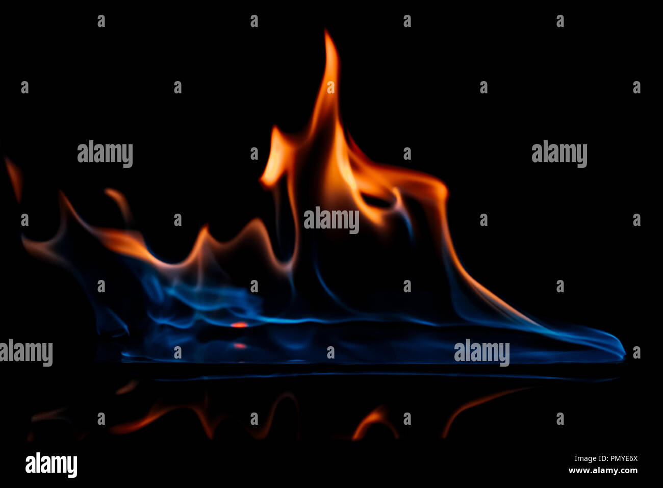 close up view of burning orange and blue flame on black background ...