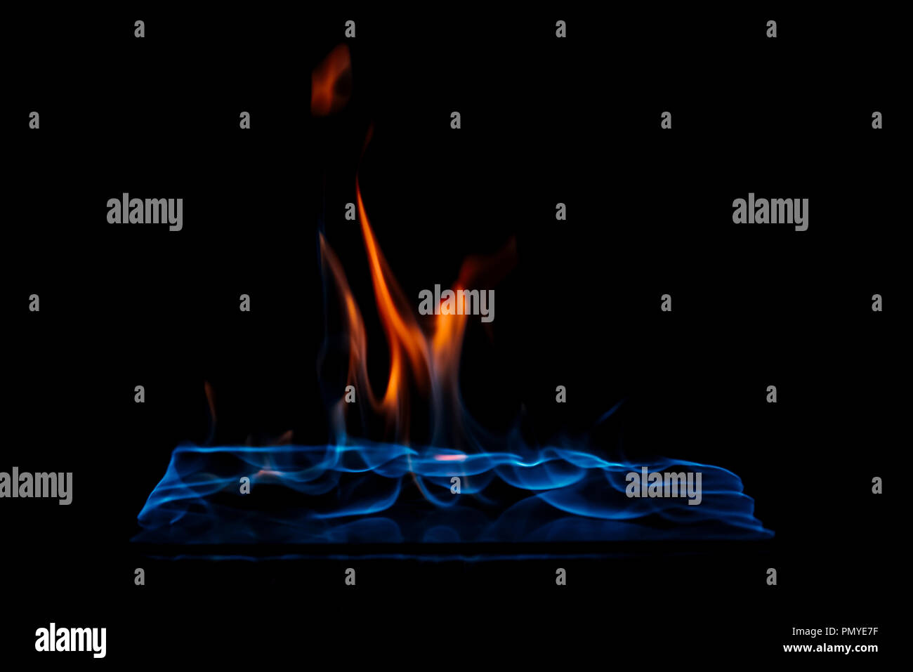 close up view of burning orange and blue flame on black background ...